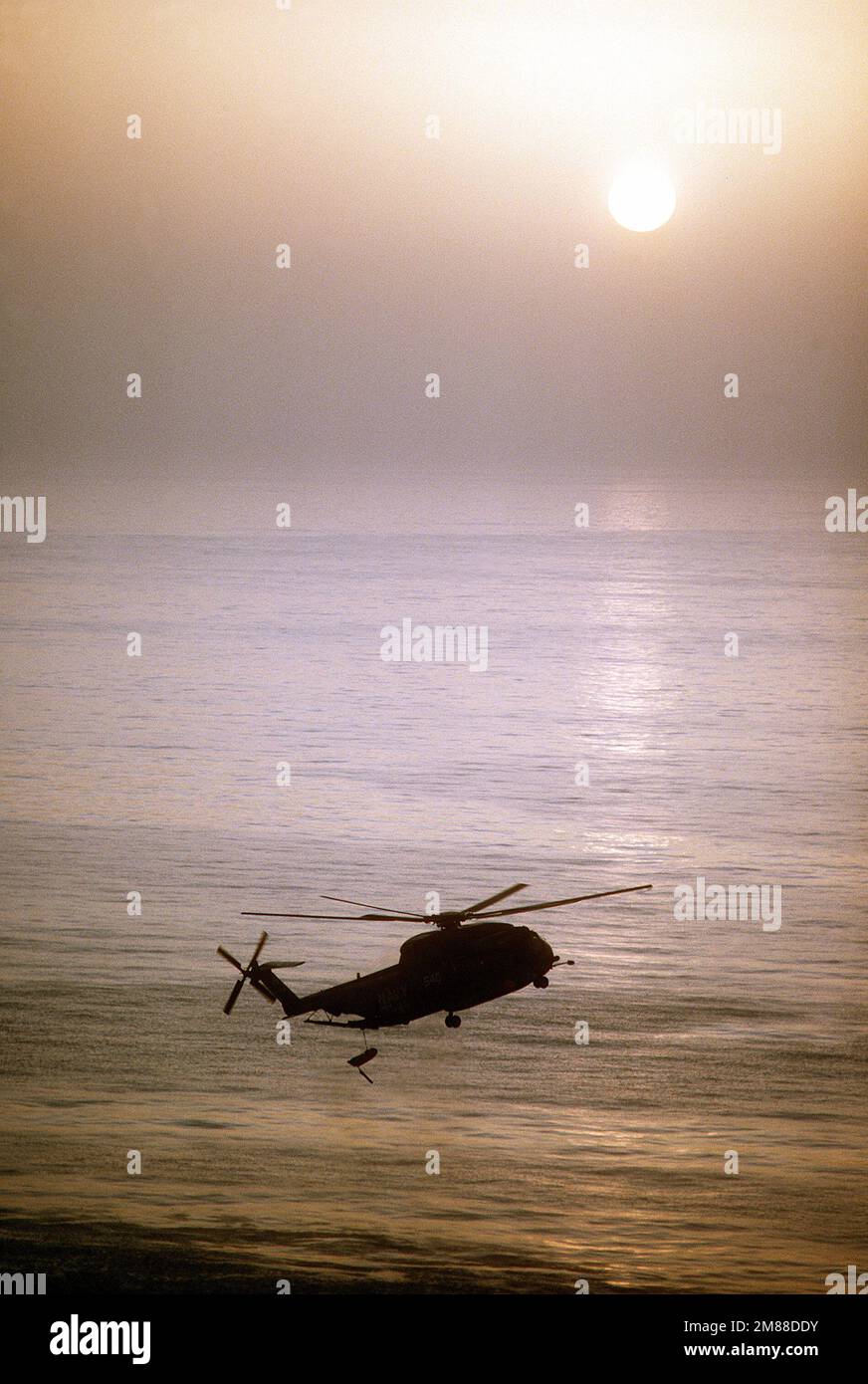A silhouetted view of an RH-53D Sea Stallion helicopter conducting a ...
