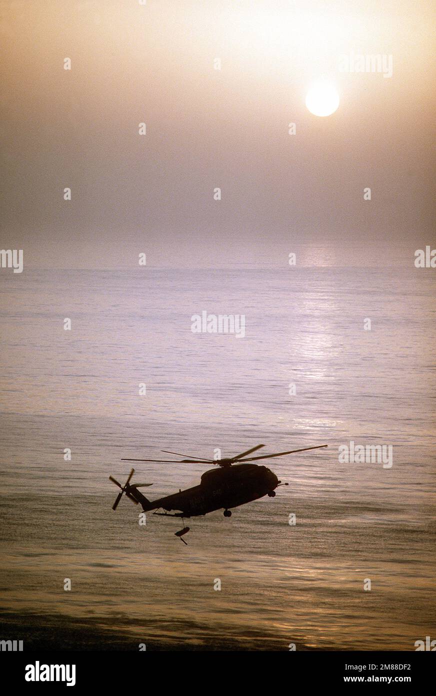 A silhouetted view of an RH-53D Sea Stallion helicopter conducting a ...