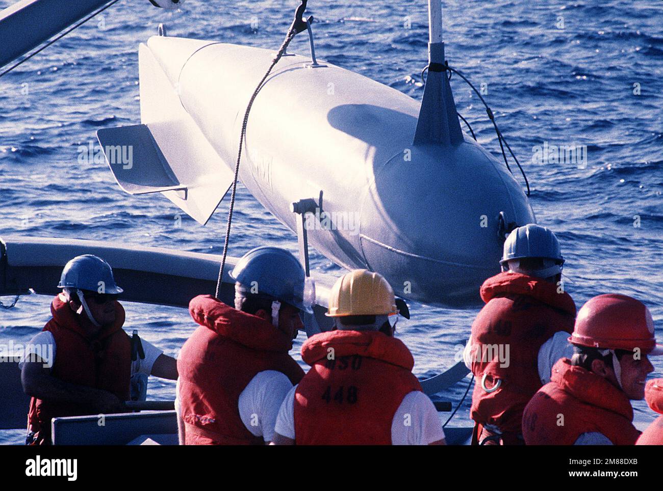 Crew members hoist a minesweeping float, known as a "pig," over the ...