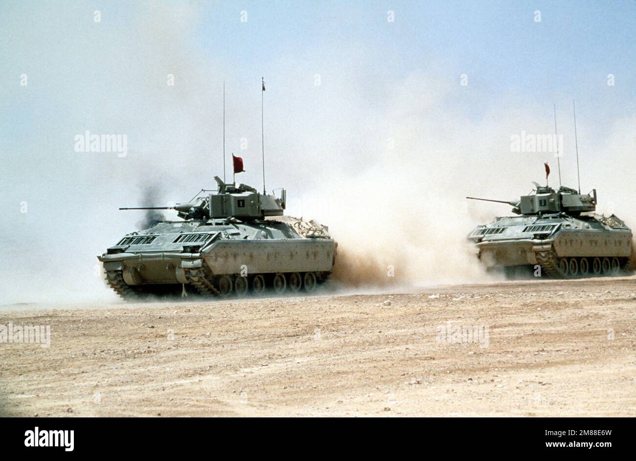 Two M-2 Bradley infantry fighting vehicles maneuver in the desert ...