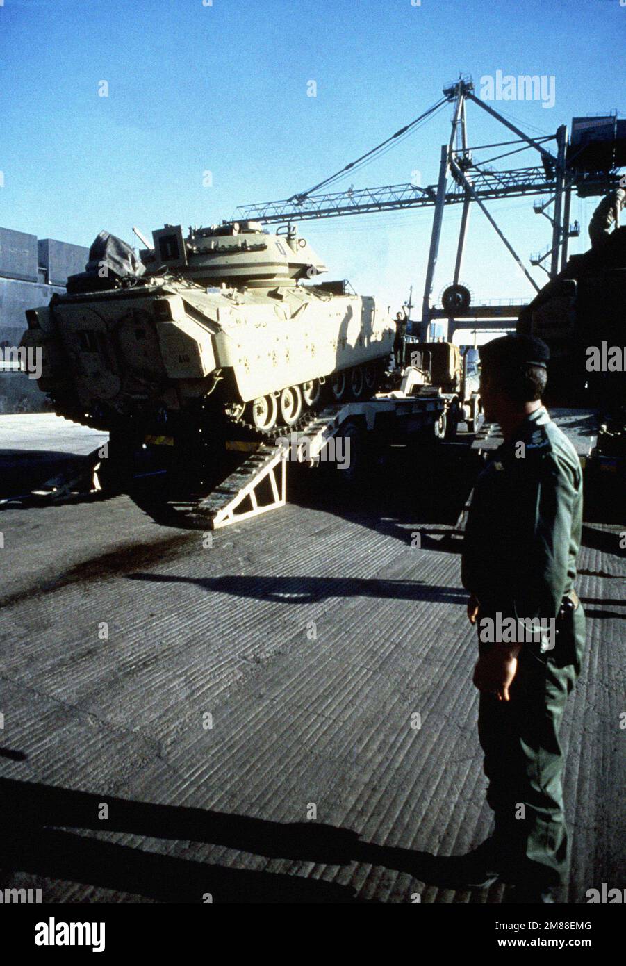 An M-2 Bradley infantry fighting vehicle is loaded onto a flatbed truck ...