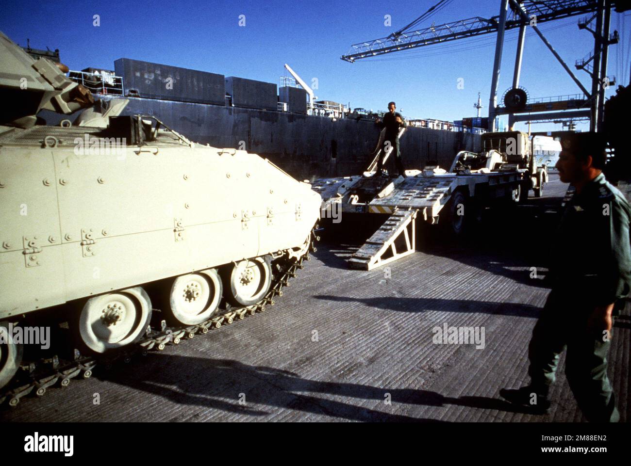 An M-2 Bradley infantry fighting vehicle is loaded onto a flatbed truck ...