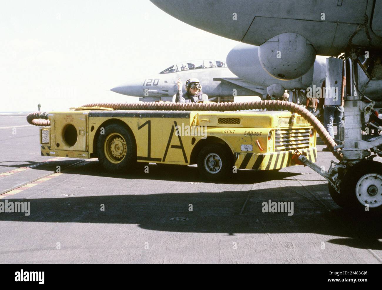 A flight deck crewman uses an MD-3A starting tractor to start an ...