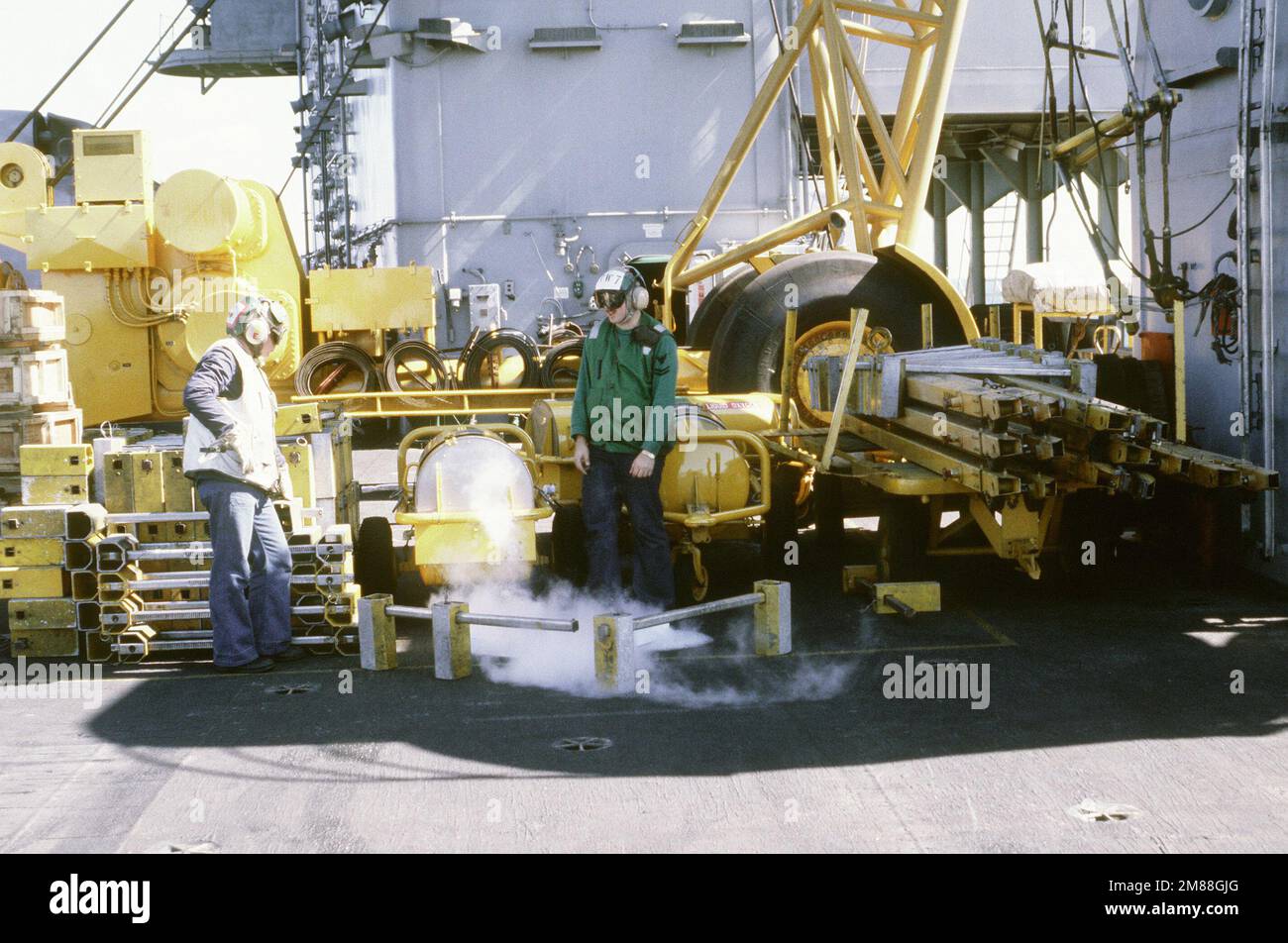 Flight deck crewmen drain liquid oxygen from a TMU-70M low-loss, closed ...