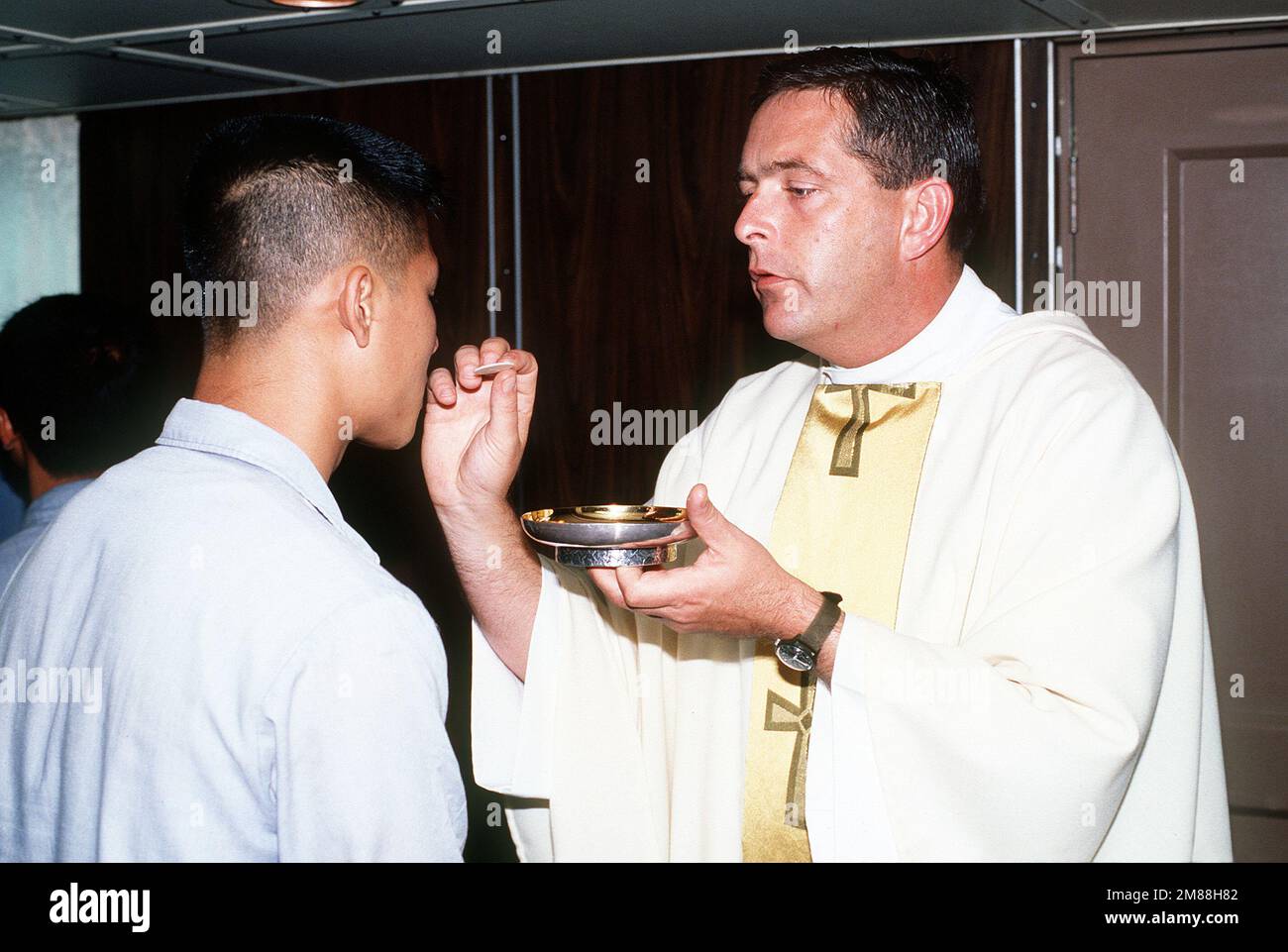 A chaplain administers Holy Communion to a crew member during Mass ...