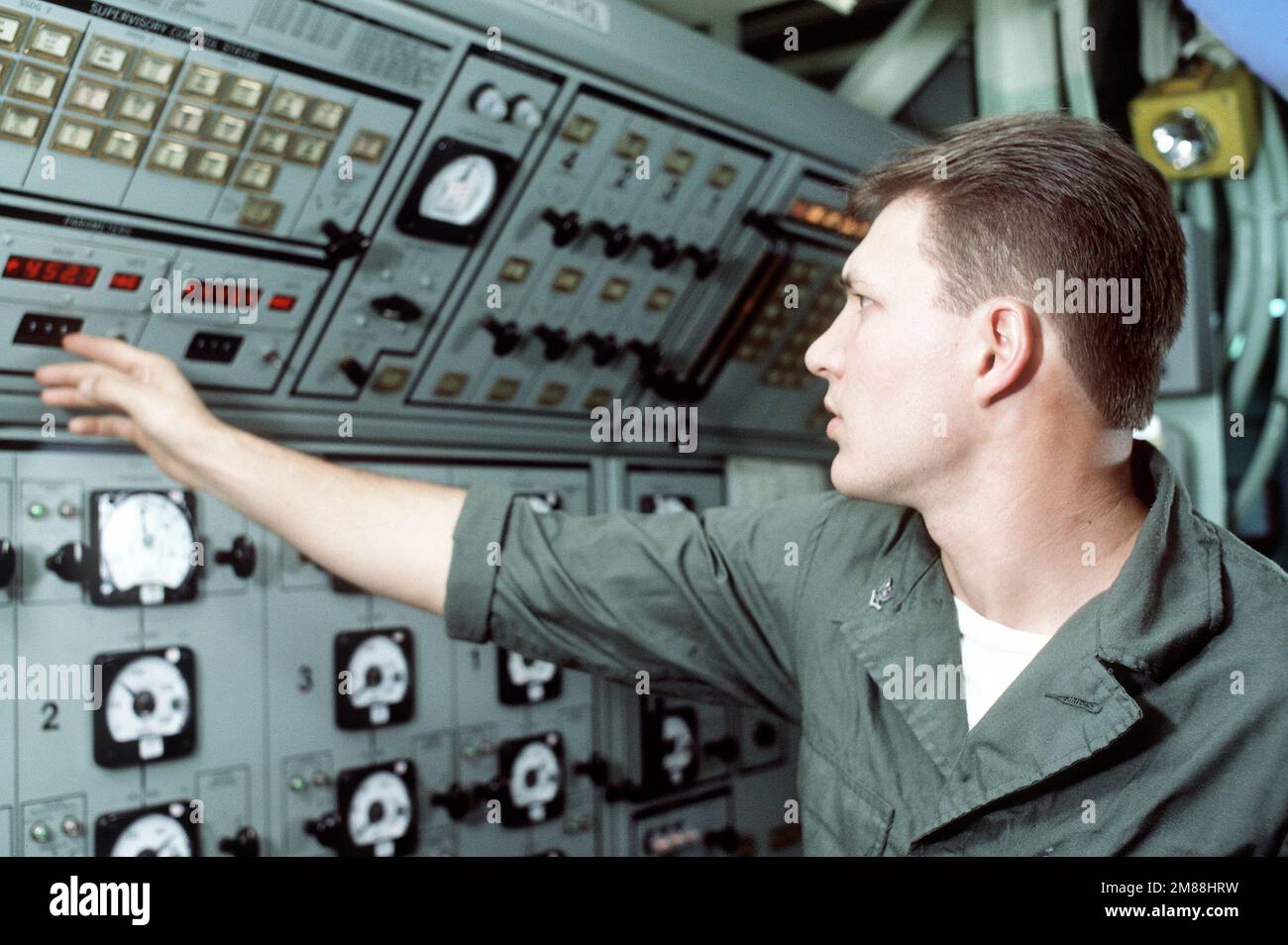 A seaman makes adjustments at the main engine control panel of a ship ...