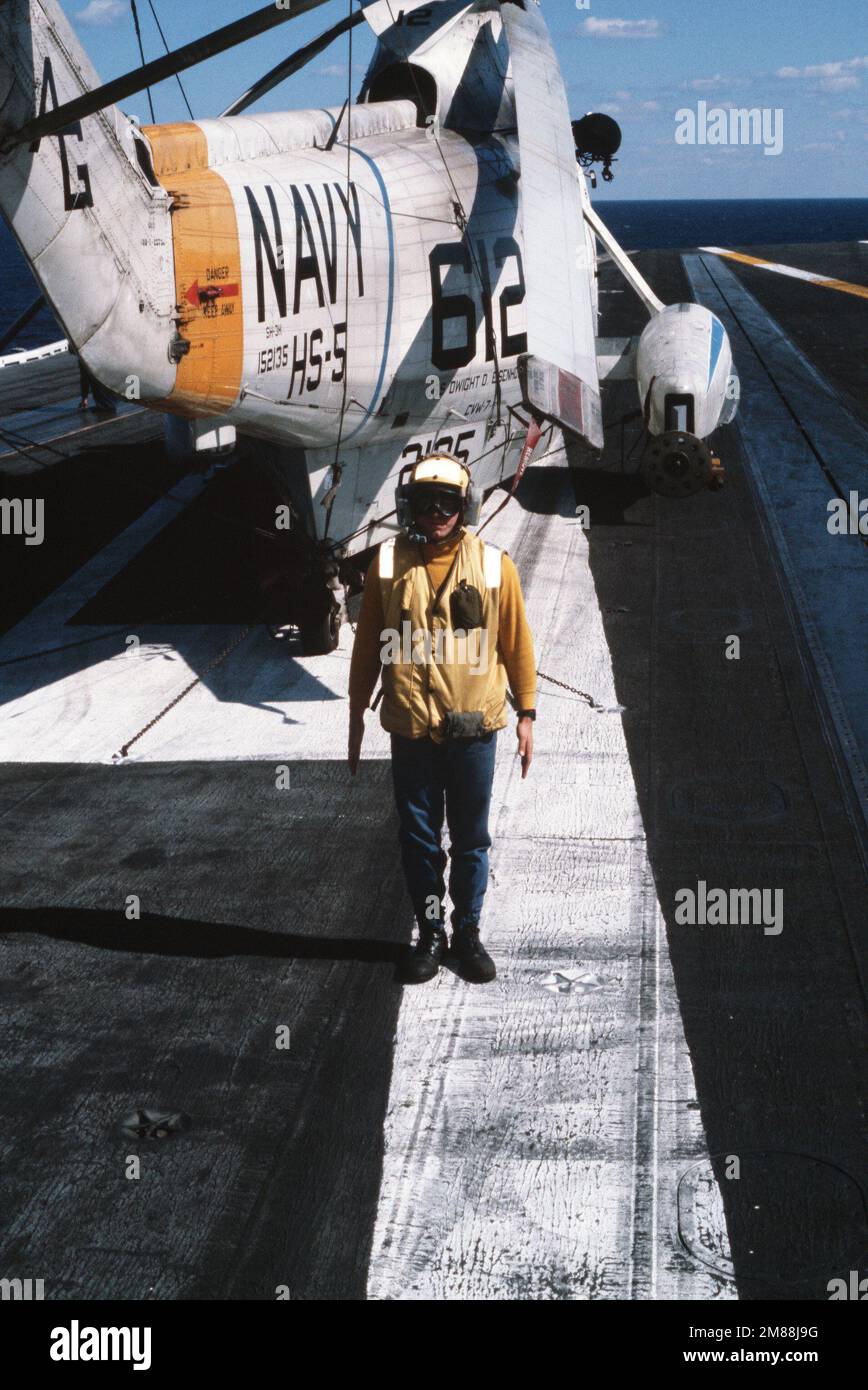A plane director gives a helicopter pilot the "slow" signal aboard the ...