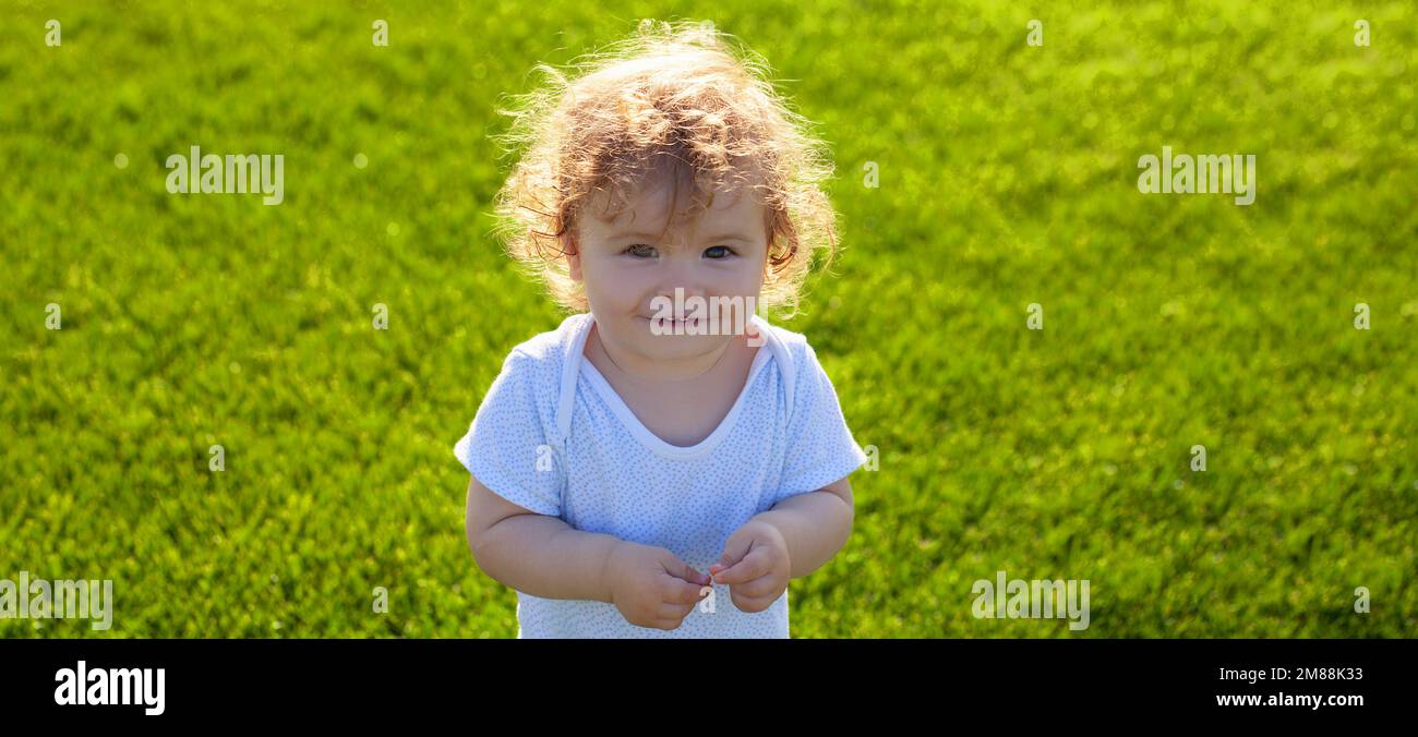 Baby on spring grass field, banner. Happy baby in grass on the fieald ...
