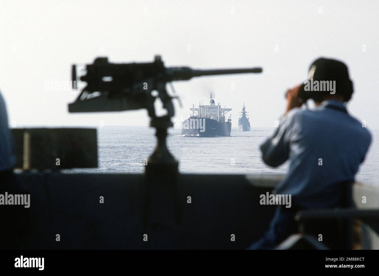A crewman stands next to an M-2 .50 caliber machine gun at the aft ...