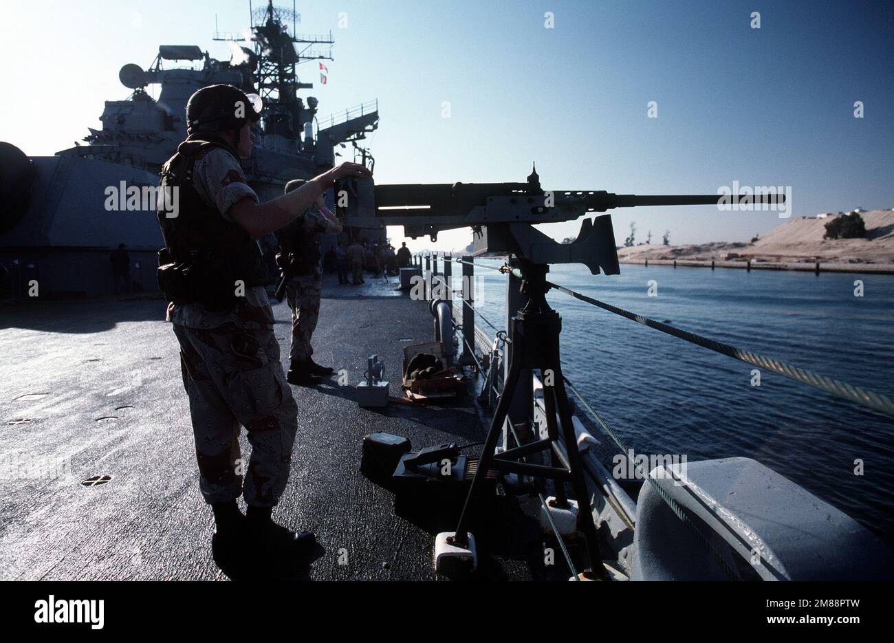 Marines, in camouflaged battle dress, man the ship's .50-cal. machine ...