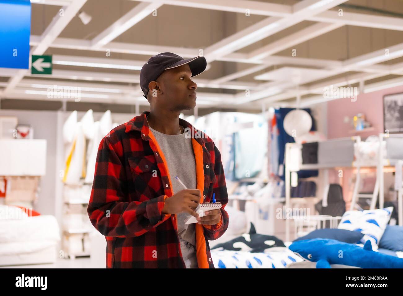 Black ethnic man shopping in a supermarket for almeadas and cushions. comparing prices Stock ...