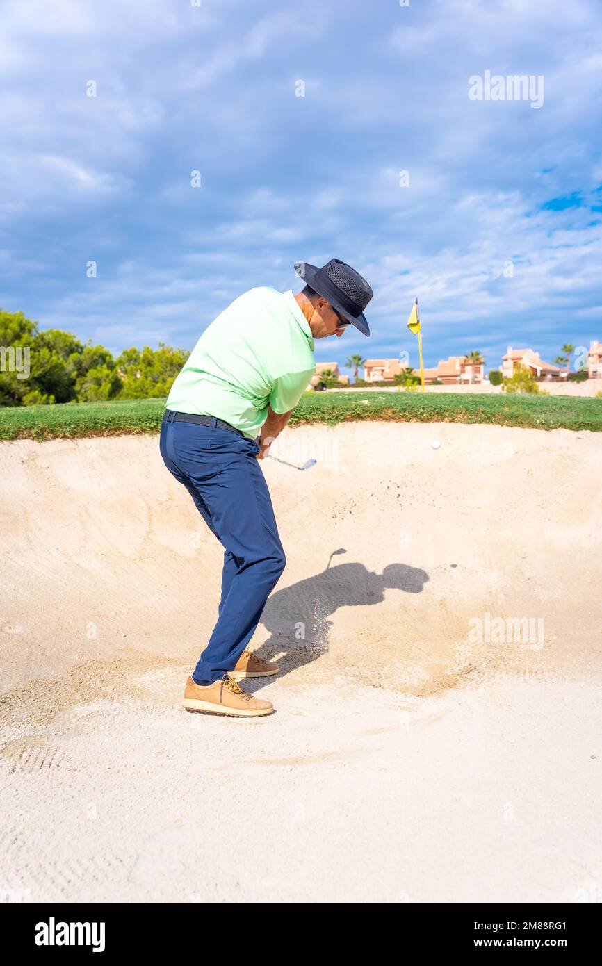 Man playing golf, getting the ball out of the bunker by hitting the ...