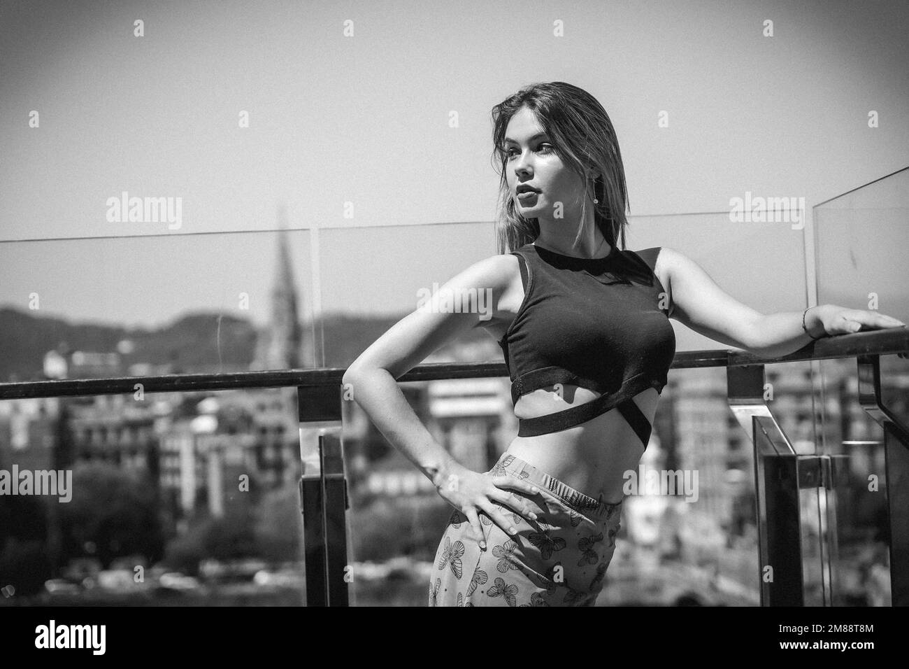 A young model in a viewpoint of the city from above, glass railing ...