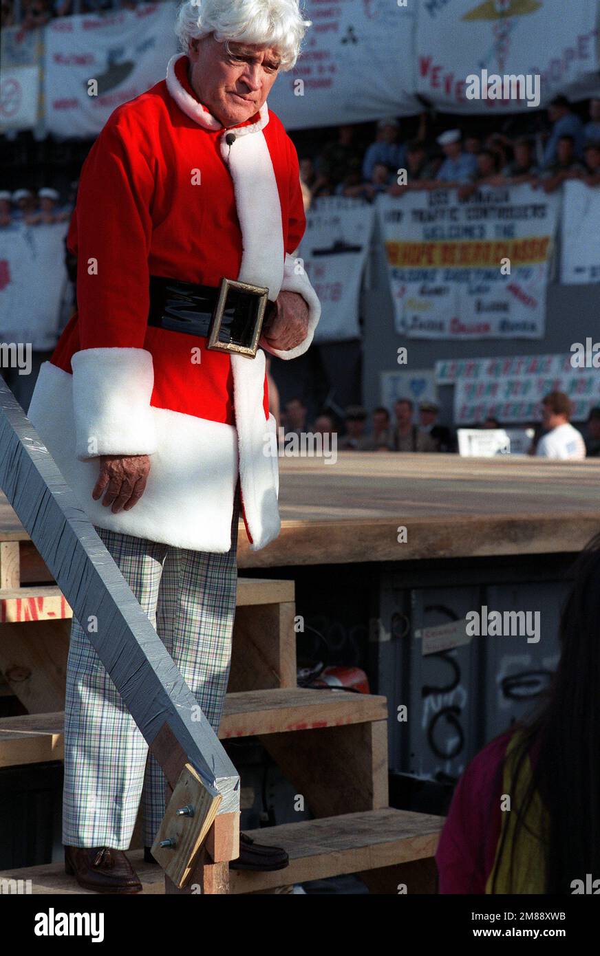 Entertainer Bob Hope stands on the steps of the stage dressed in a red ...