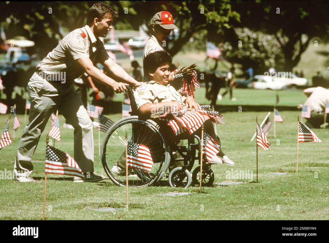 Three Boy Scouts, one in a wheelchair, place American flags on the ...
