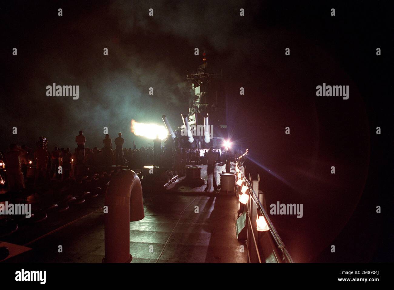 Crew members watch a night firing of the No. 3 Mark 7 16-inch/50 ...
