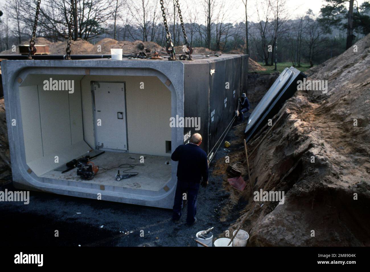 A worker watches as his companion uses a device to pull a prefabricated ...