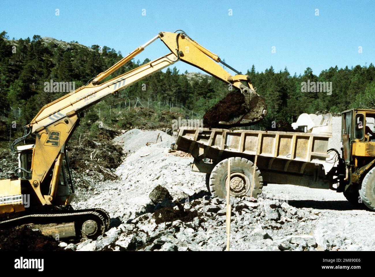 A shovel deposits backfill in a dump truck at a construction site ...