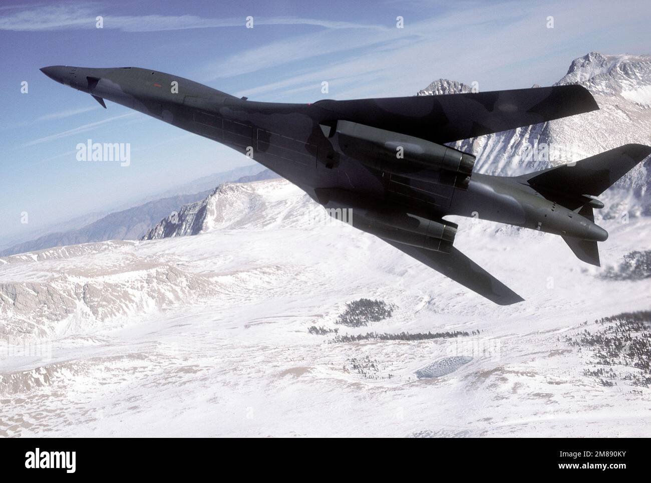 An air-to-air left side view of a B-1B aircraft banking into a right ...