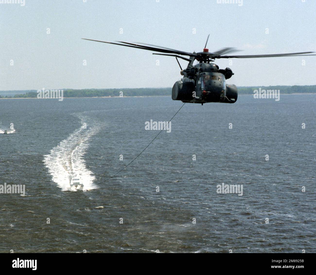 An air-to-air front view of an MH-53E Sea Dragon helicopter towing a ...