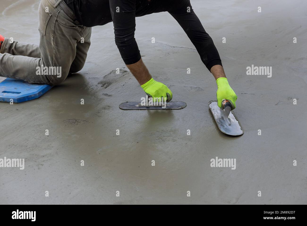 During plastering of concrete to cement floor masonry worker holds ...