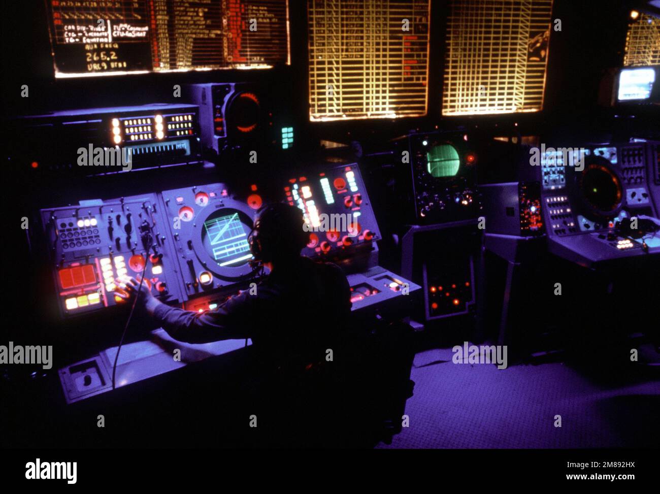 A crewman monitors a console in a shipboard combat information center ...