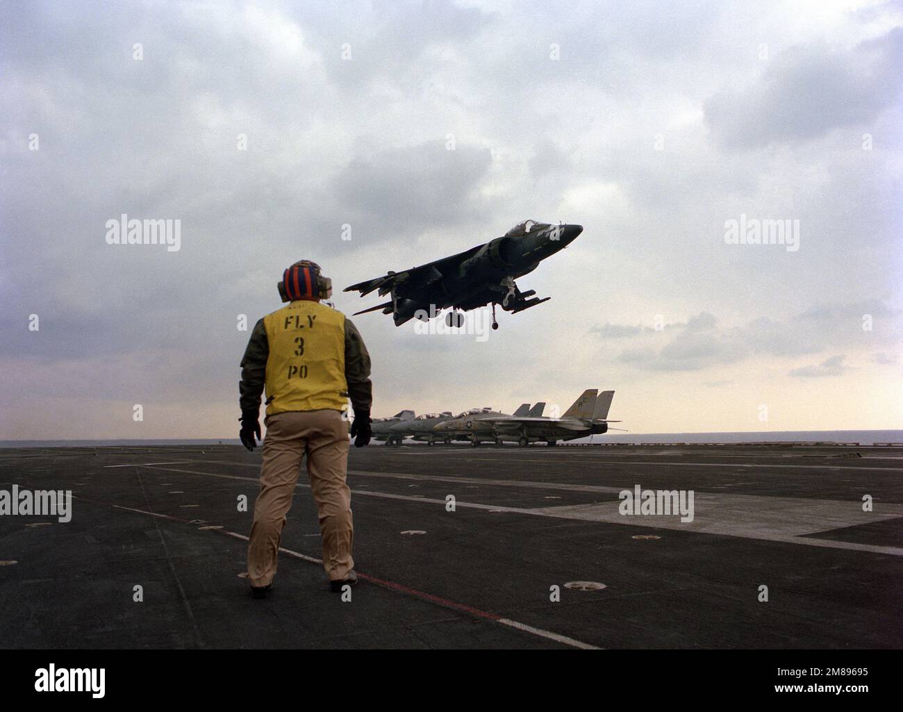 A flight deck officer watches as an AV-88 Harrier aircraft of Marine ...