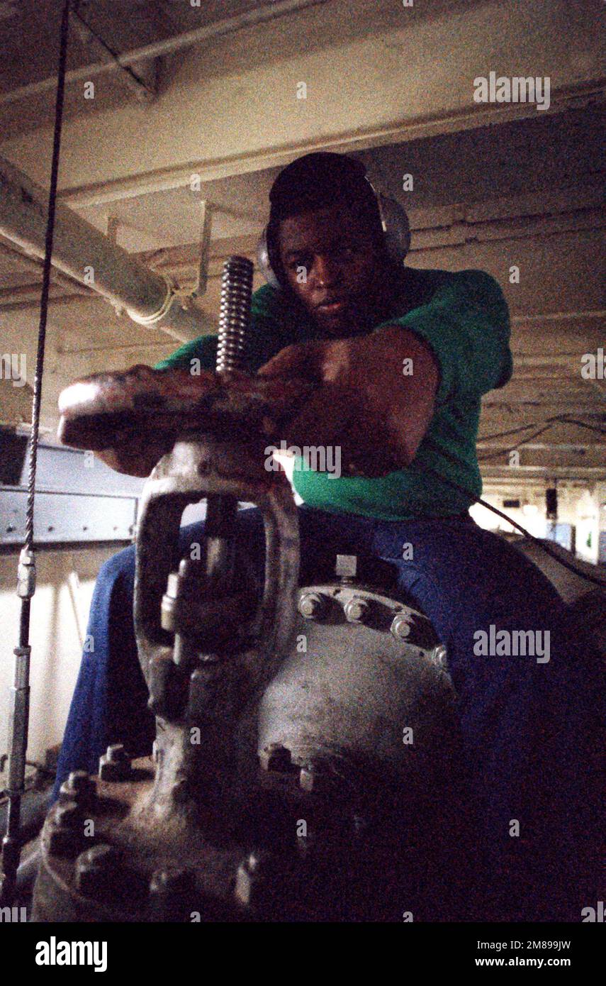 A crewman makes a valve adjustment to a Mark 7 arresting engine beneath ...