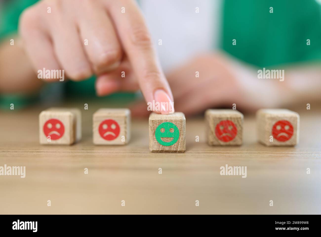 Woman's hand chooses happy emoji from wooden cubes with sad and happy ...
