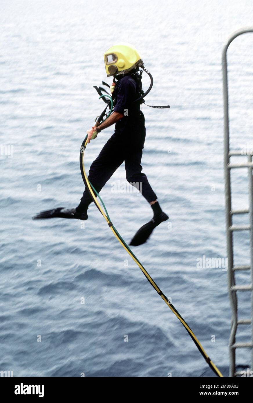 A Navy diver from Mobile Diving Salvage Unit One enters the water from ...