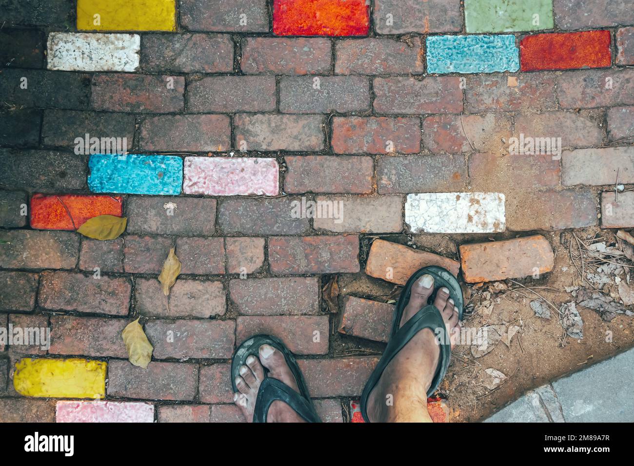 Feet of man wear sandals on old beautiful multicolor bricks paving ...