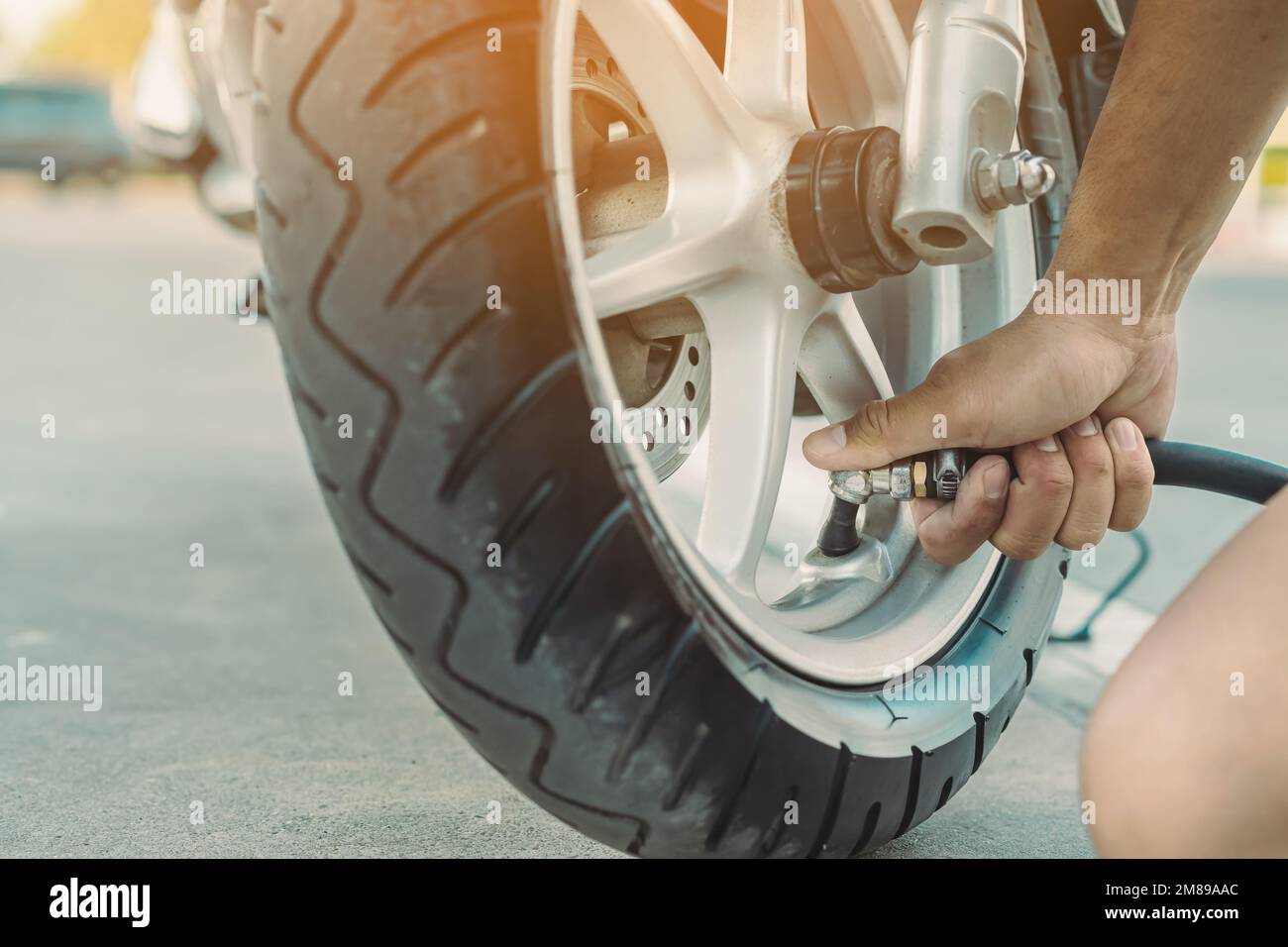 Hands of man check inflator pressure and inflates a tire on motorcycle ...