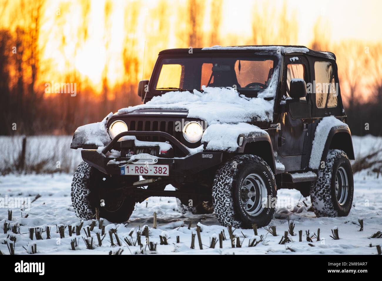 A Jeep wrangler covered in snow at sunset on a cold winter day Stock ...