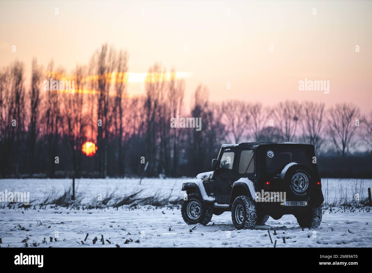 A Jeep wrangler covered in snow at sunset on a cold winter day Stock ...