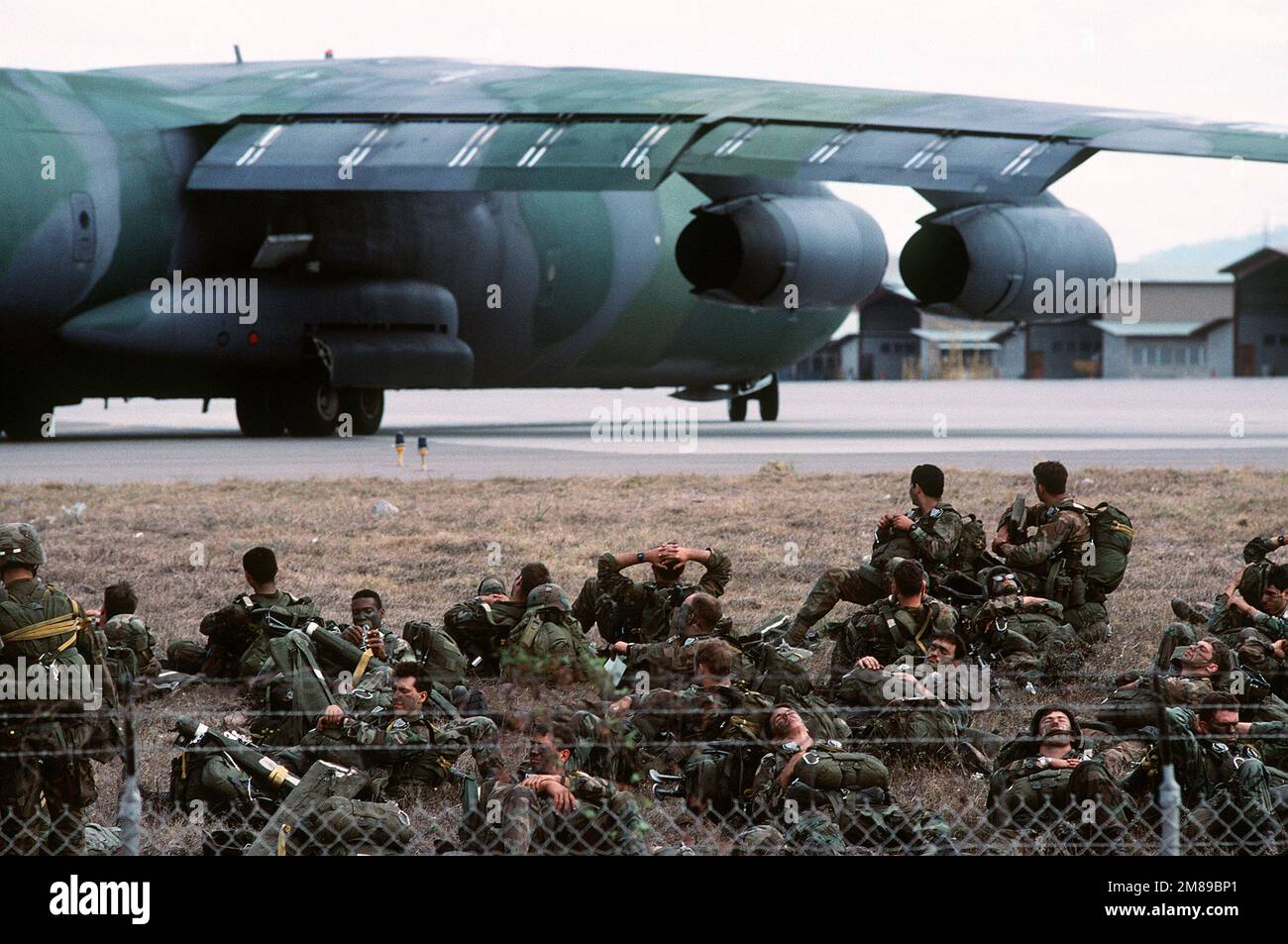 Members of the 82nd Airborne Division wait as a C-141B Starlifter ...