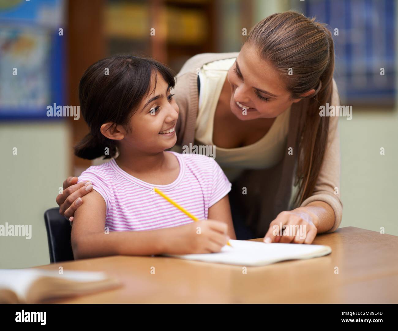 Shes proud of her progress. a teacher helping her student with her work ...