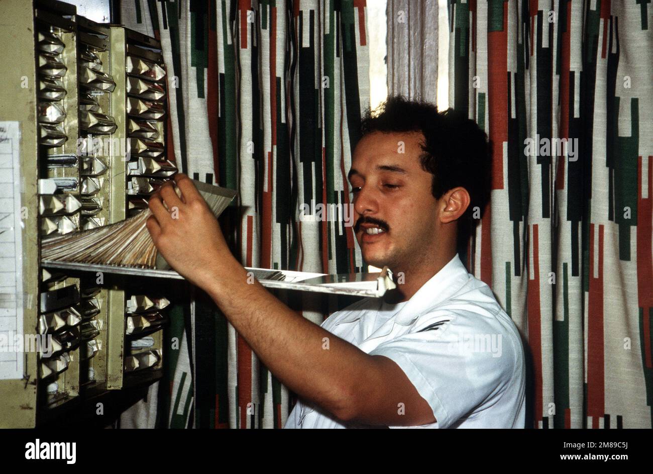 A sailor files room inventory cards in the office of a Bachelor ...