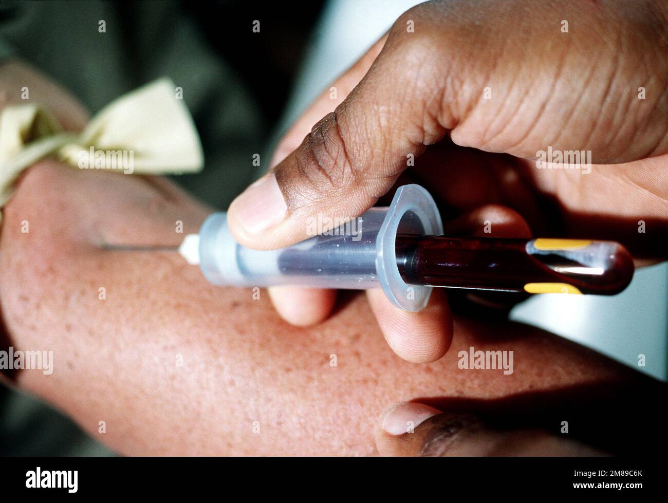 A corpsman uses a syringe to draw a patient's blood for testing at the ...