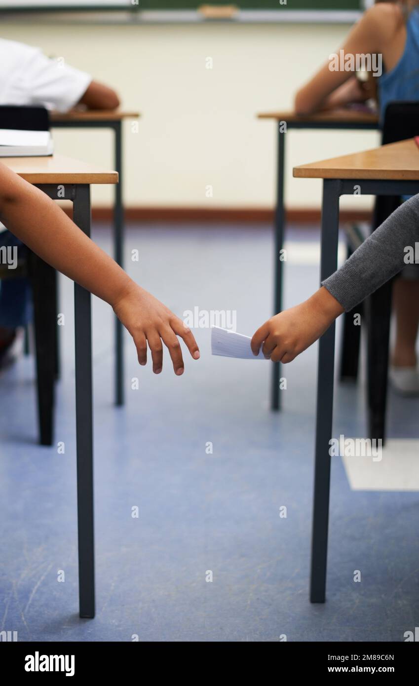 Passing a note. two students passing notes during class Stock Photo - Alamy