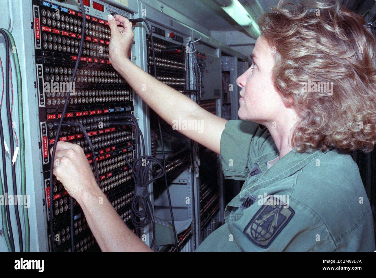 A soldier checks a switchboard panel in a telephone operations center ...