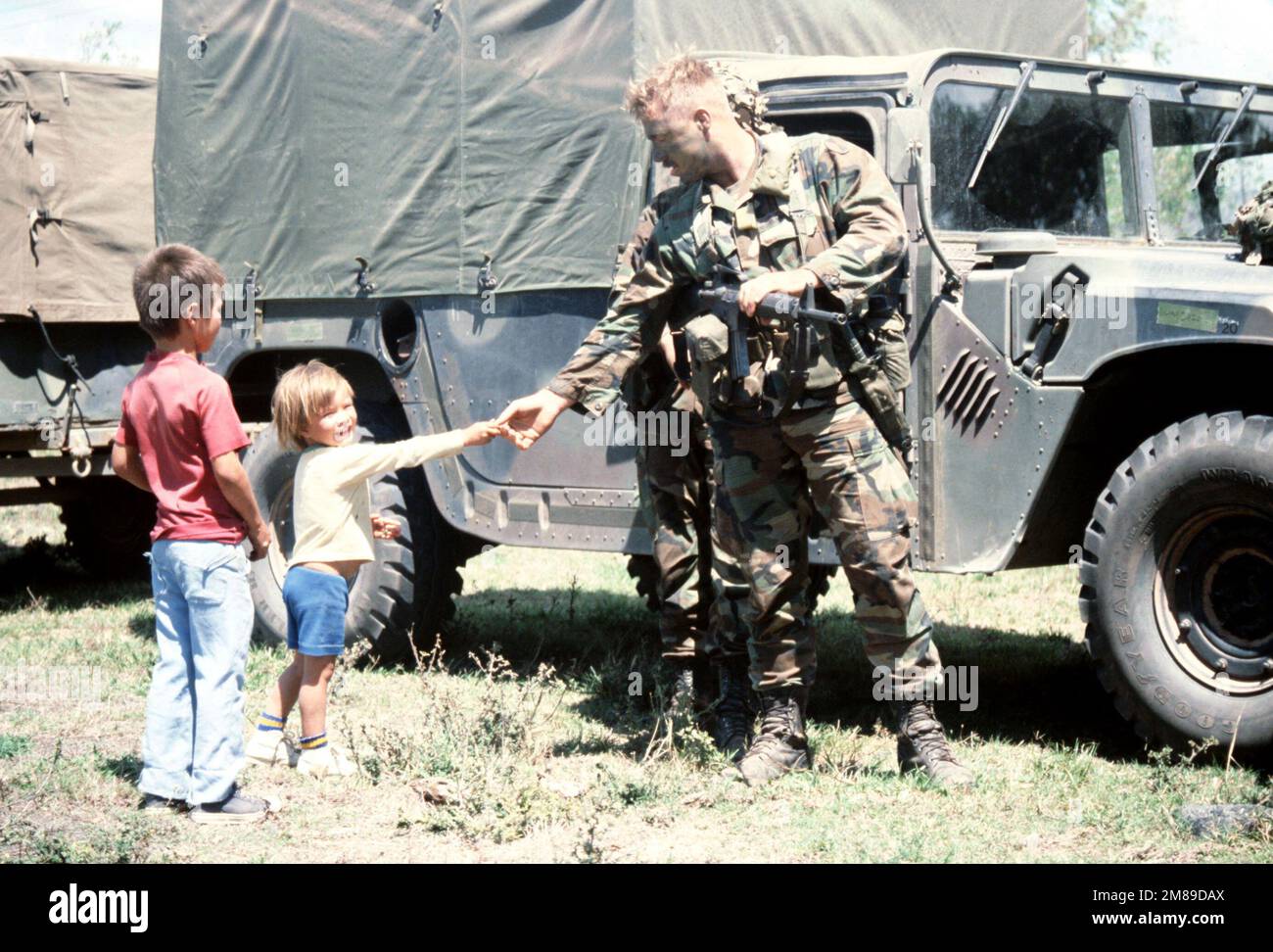 A 7th Infantry Division soldier gives some food to a Honduran child ...