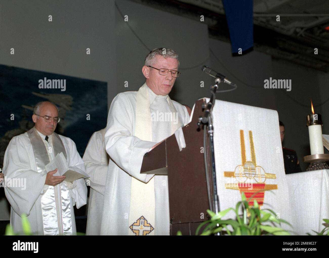 A chaplain stands at a lectern to read during an interfaith Easter ...