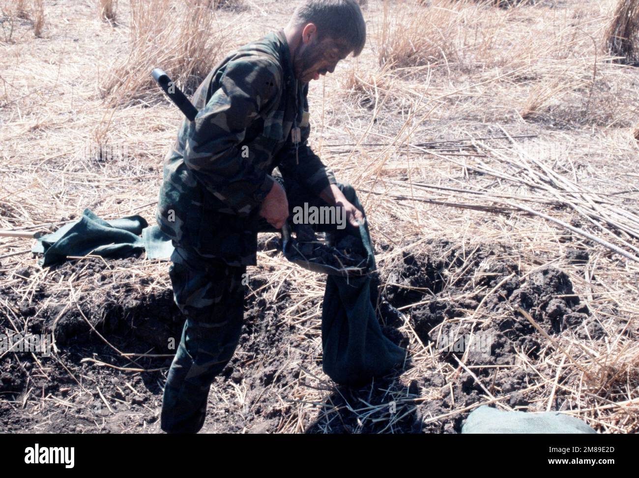 A member of the 82nd Airborne Division fills a sandbag with dirt during ...