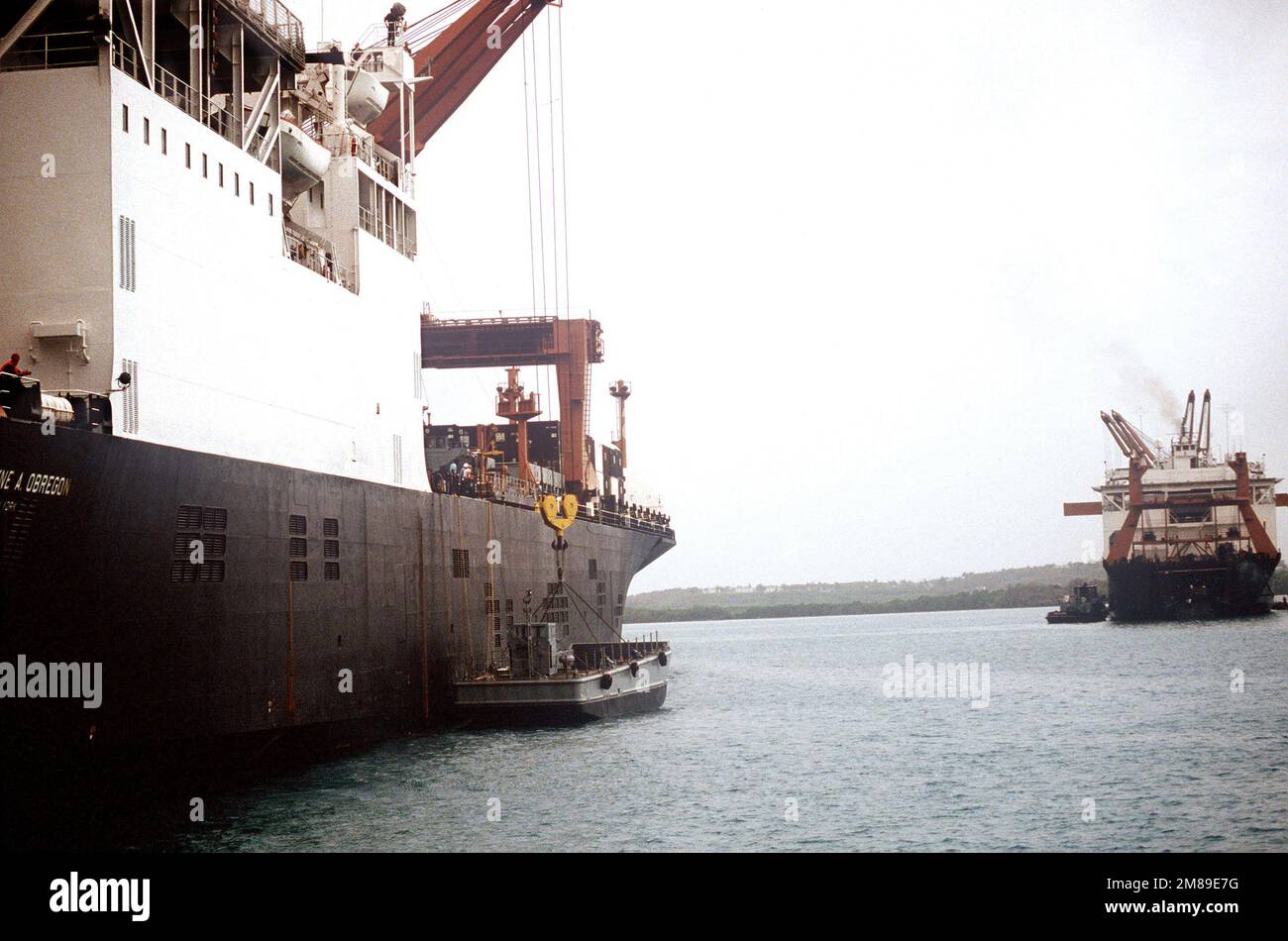 An LCM-8 mechanized landing craft is lowered into the water by a crane ...