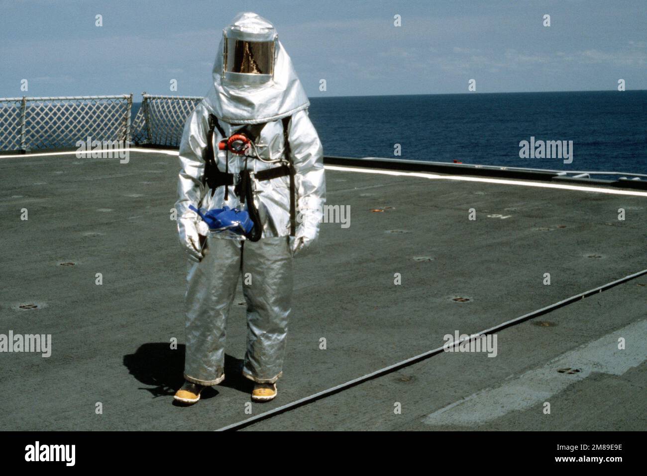 A Marine dressed in a proximity suit stands on the flight deck of the ...
