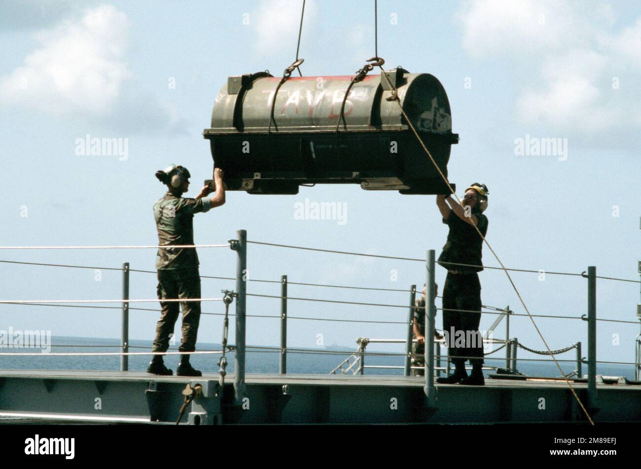 Two Marines guide an engine container as it is lowered onto the ...