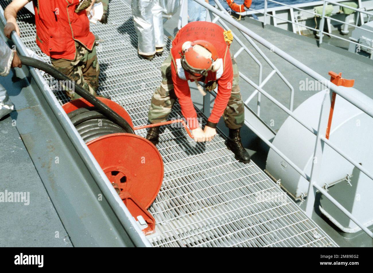 A Marine rewinds a fire hose into its spool at the edge of the flight ...