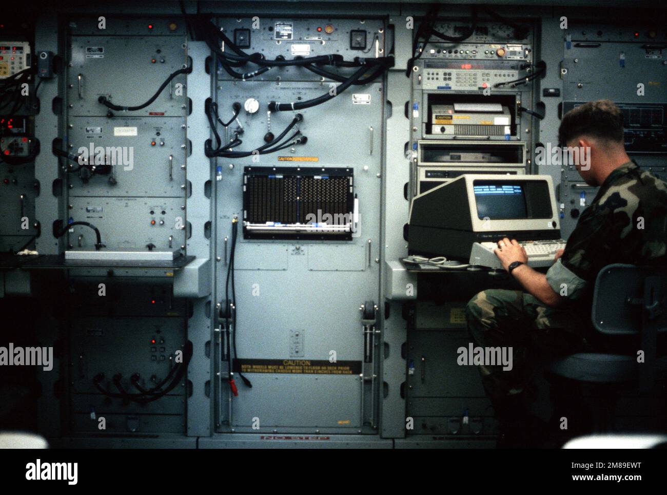 A Marine monitors a computer in a shelter stored in the cargo hold of a ...