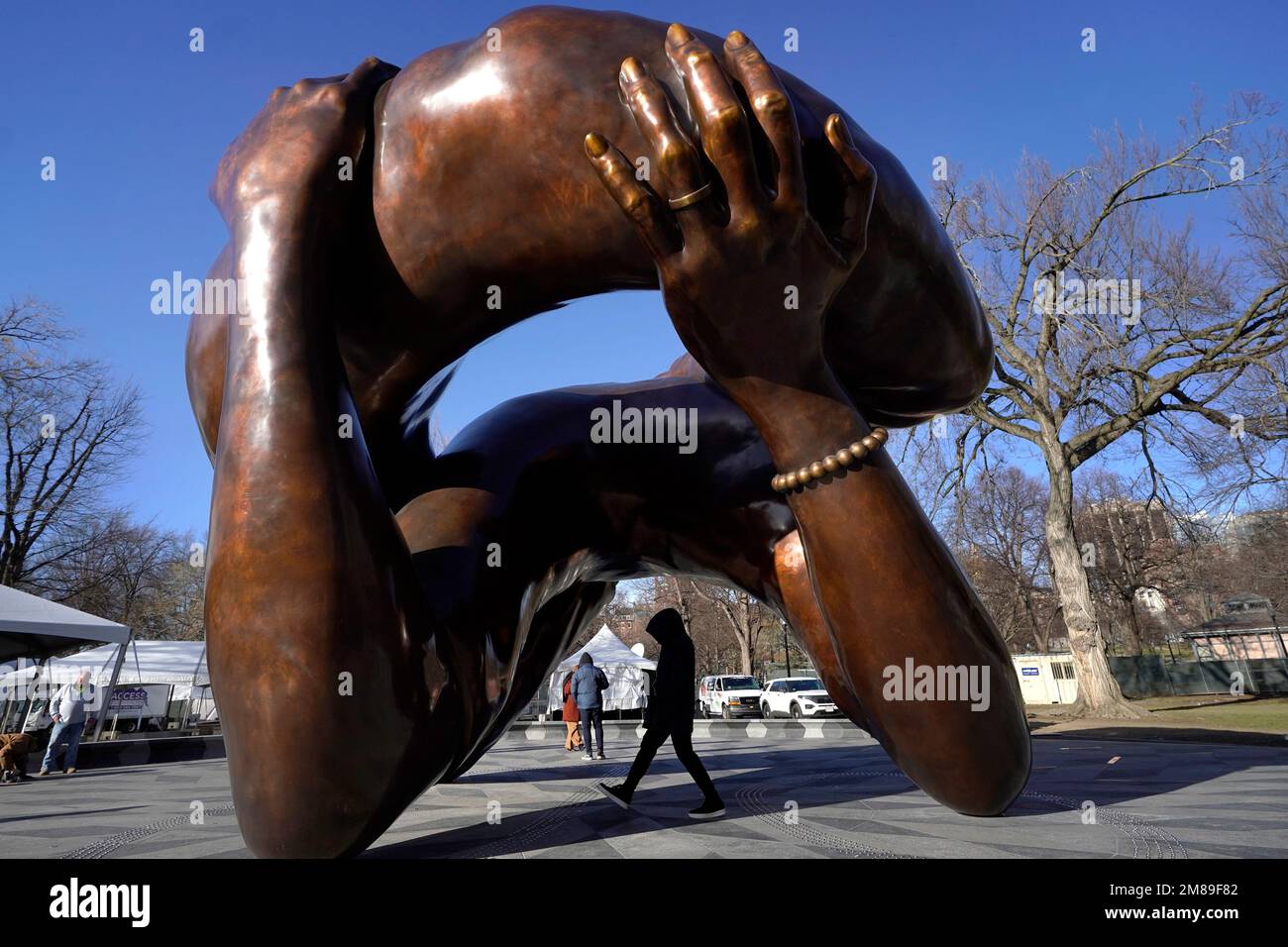 A passer-by walks under the 20-foot-high bronze sculpture "The Embrace ...