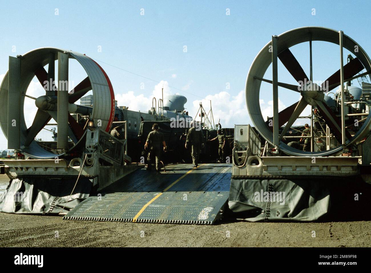Two crewmen walk up the stern ramp of an air cushion landing craft ...